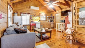 Interior acolhedor de uma cabana de madeira, com sala de estar, cozinha e área de jantar.