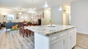 Uma cozinha moderna com bancada de granito, armários brancos e iluminação pendente.