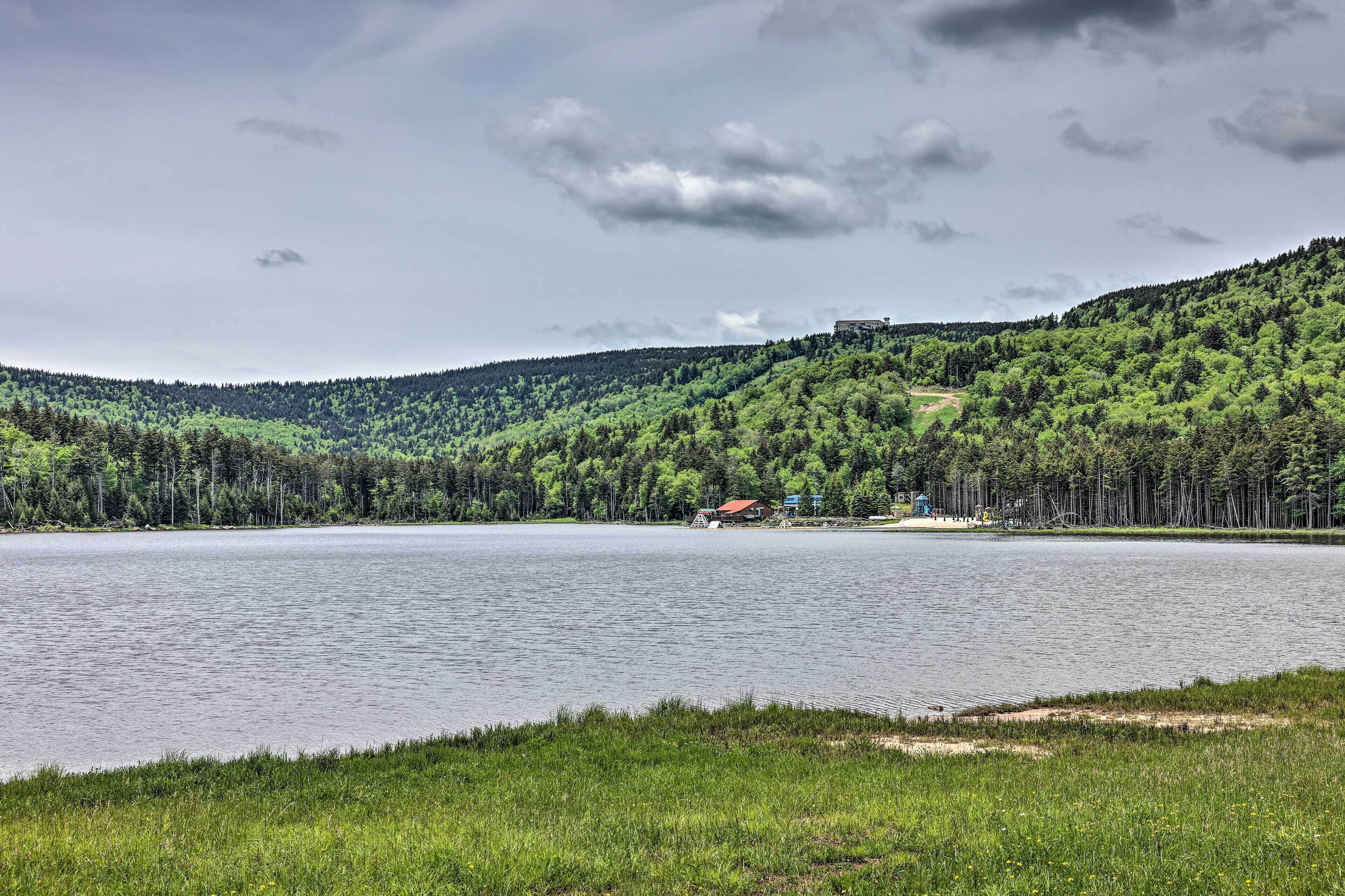 Um lago rodeado por colinas arborizadas, com um pequeno edifício no topo.