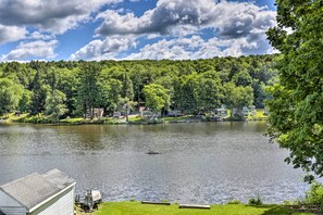 Um lago com um píer, rodeado por vegetação exuberante e edifícios residenciais.