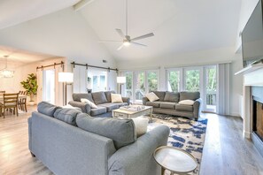 Uma sala de estar espaçosa com um amplo sofá modular cinza, uma mesa de centro e uma lareira.