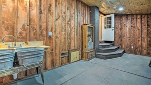 Casa de banho rústica com paredes de madeira, lavatório duplo, espelho e porta para outro espaço.