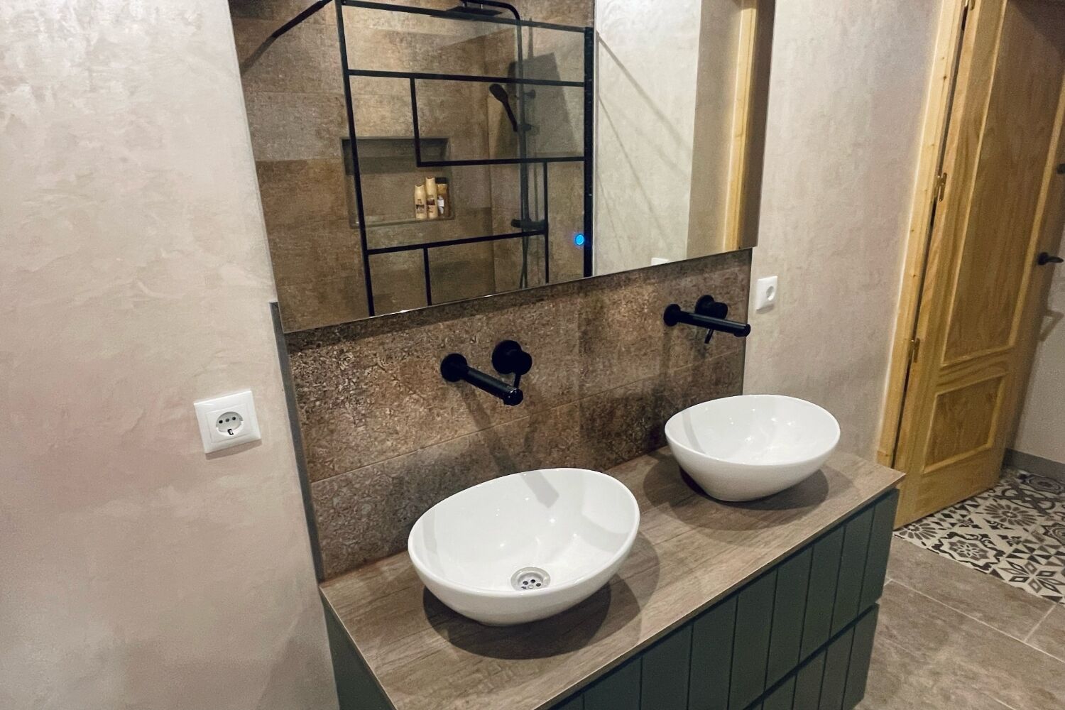 Casa de banho com duas pias brancas, um espelho e zona de duche.
