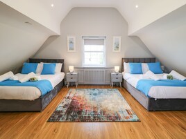 Quarto moderno com duas camas, uma janela grande e um tapete colorido.