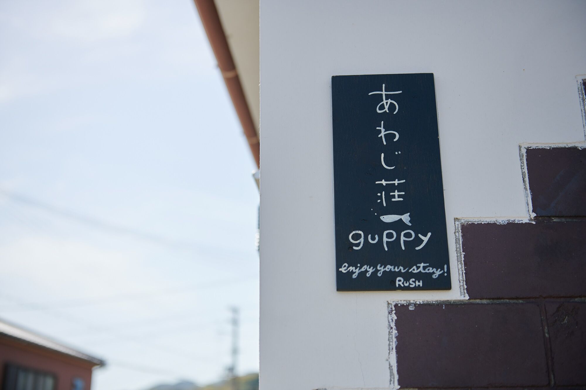 Um letreiro na parede com caracteres japoneses e a palavra 'goppy' escrita abaixo.