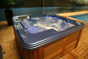 Uma banheira de hidromassagem com deck de madeira e vista para um lago.