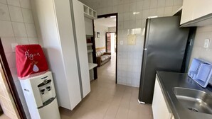Cozinha moderna com armários brancos, geladeira de aço inoxidável e dispenser de água.