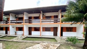 Um edifício de vários andares com telhado plano, varandas múltiplas e um pátio com caminhos de pedra.