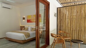 Quarto com cama, uma cadeira, uma mesinha e um separador de bambu.