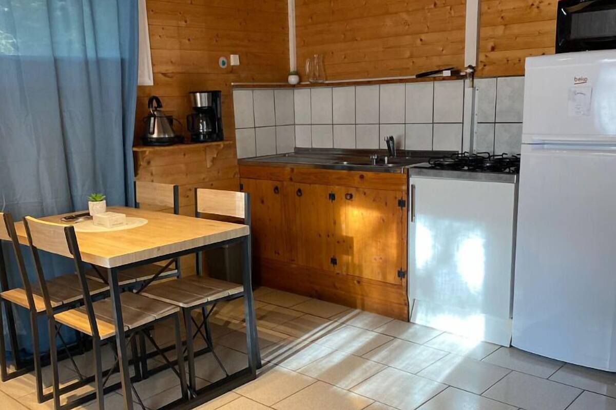 Uma cozinha compacta com bancada de madeira, geladeira branca e mesa de jantar com cadeiras.