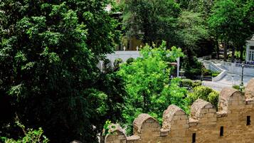Um muro de pedra com arcos, árvores verdejantes e um edifício ao fundo.