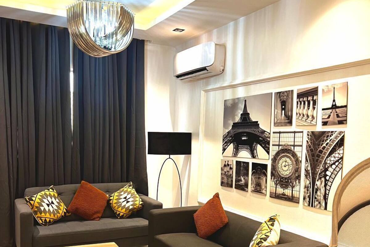 Uma sala de estar moderna com um sofá, uma mesa de centro, um tapete e um candelabro.