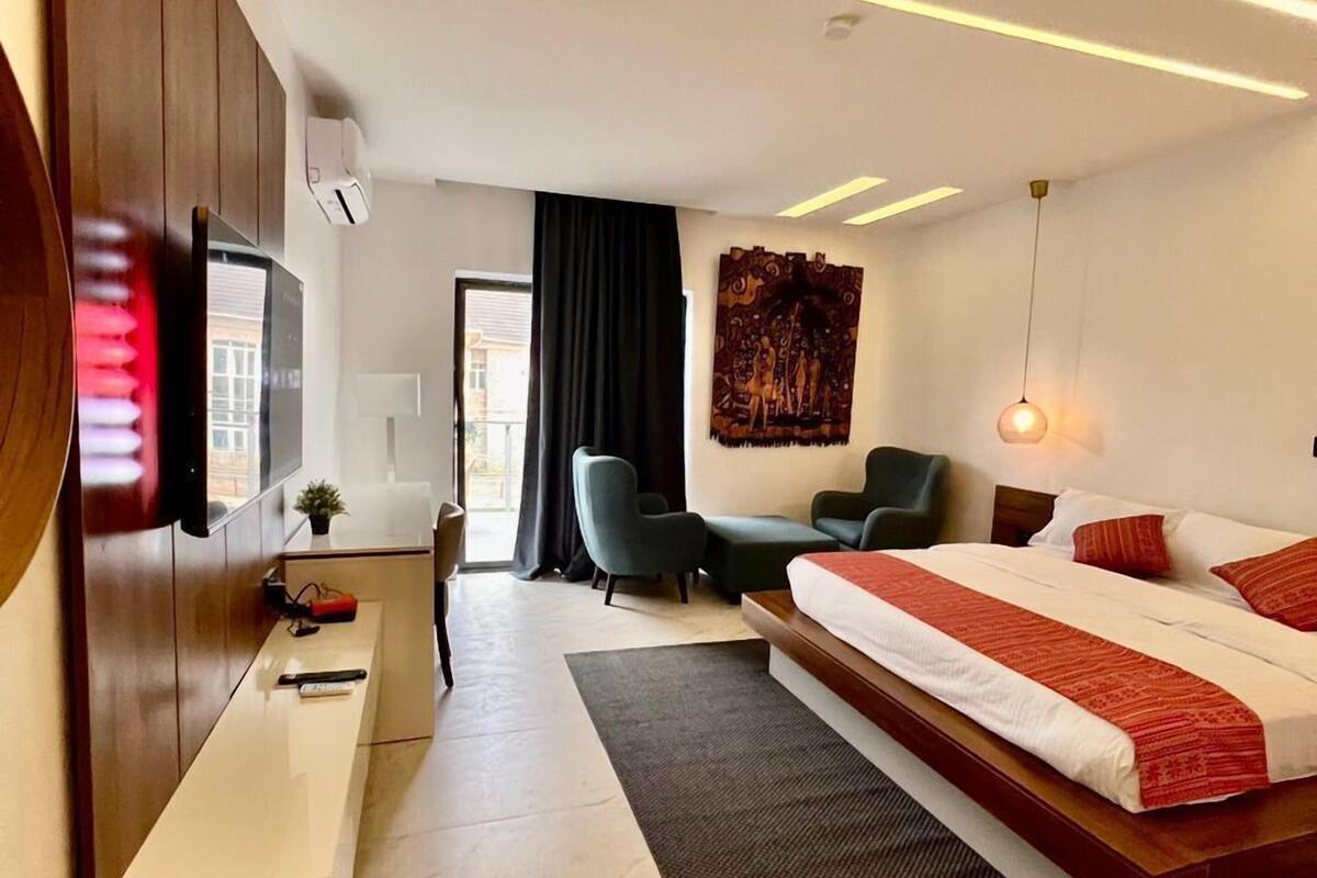 Quarto de hotel moderno com cama, área de estar e televisão.