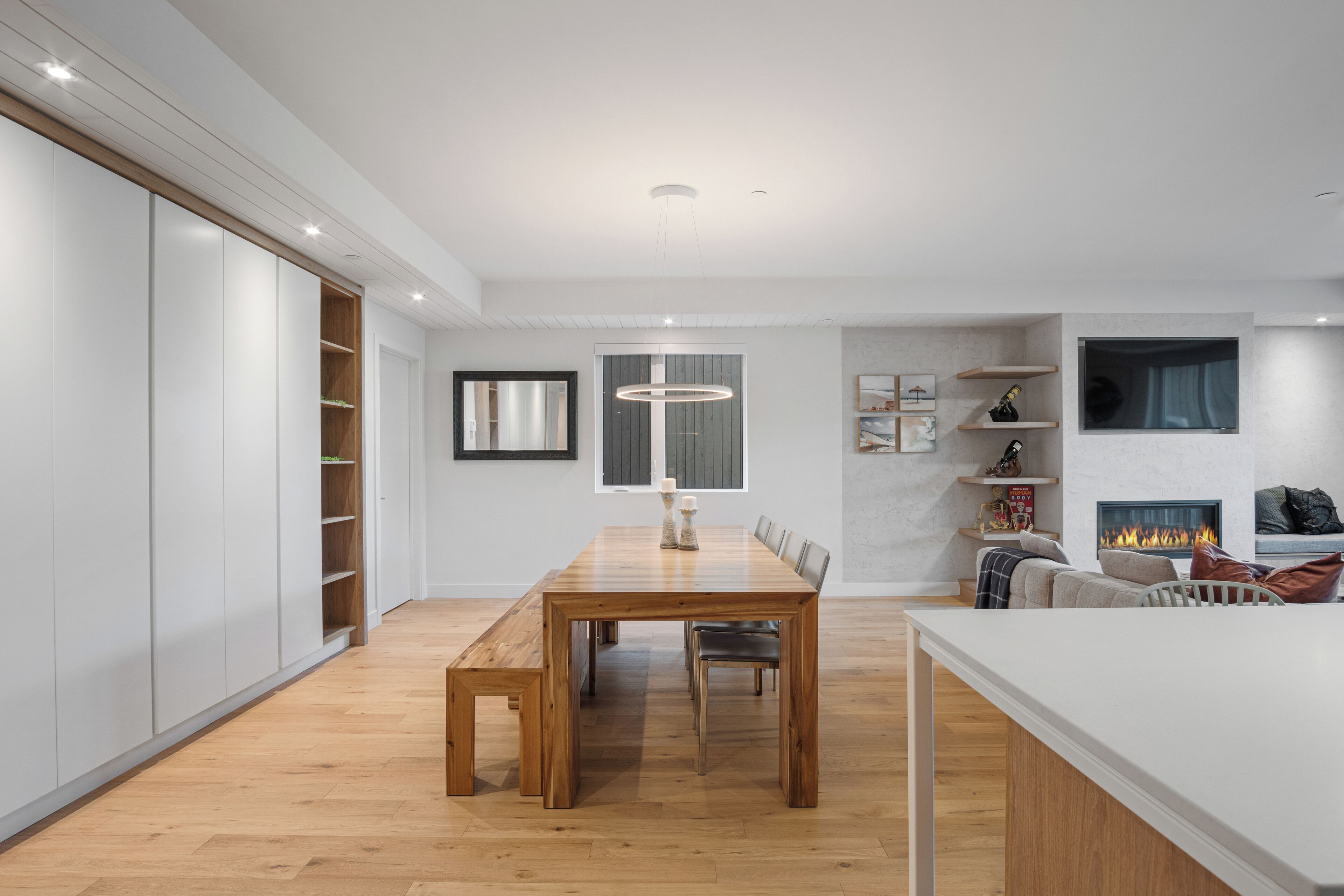 Uma sala de estar moderna com uma mesa de jantar de madeira, lareira e um sofá.