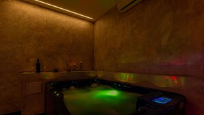 Uma banheira de hidromassagem com painel digital, rodeada por paredes texturizadas e piso de madeira.