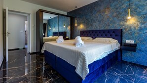 Quarto de hotel moderno com uma cama grande, um espelho e uma parede azul com textura.