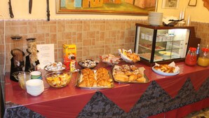 Uma mesa de buffet com diversos alimentos, incluindo doces, frutas e acompanhamentos.