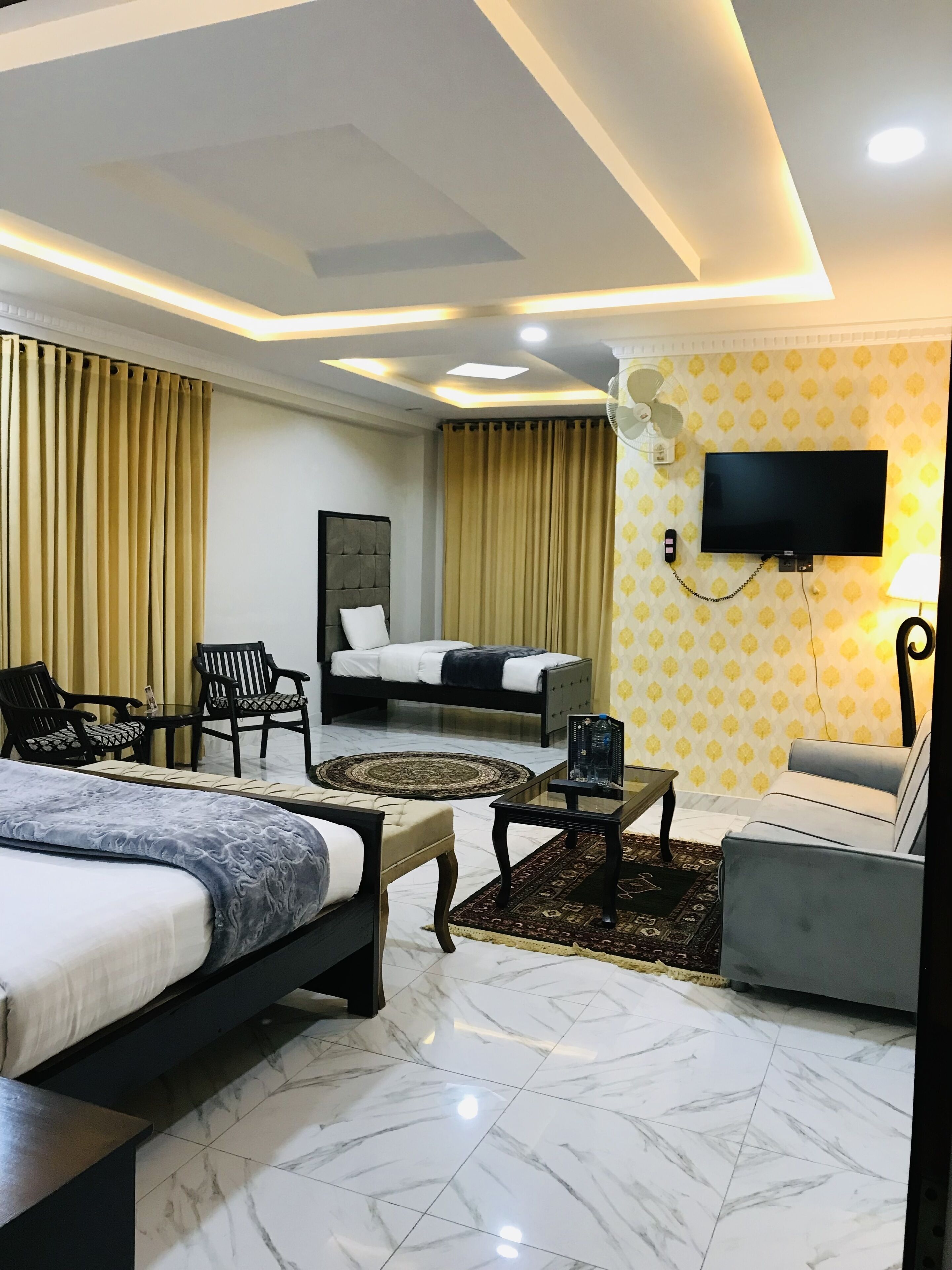 Quarto de hotel com cama, sofá, televisão, escrivaninha e cadeira.