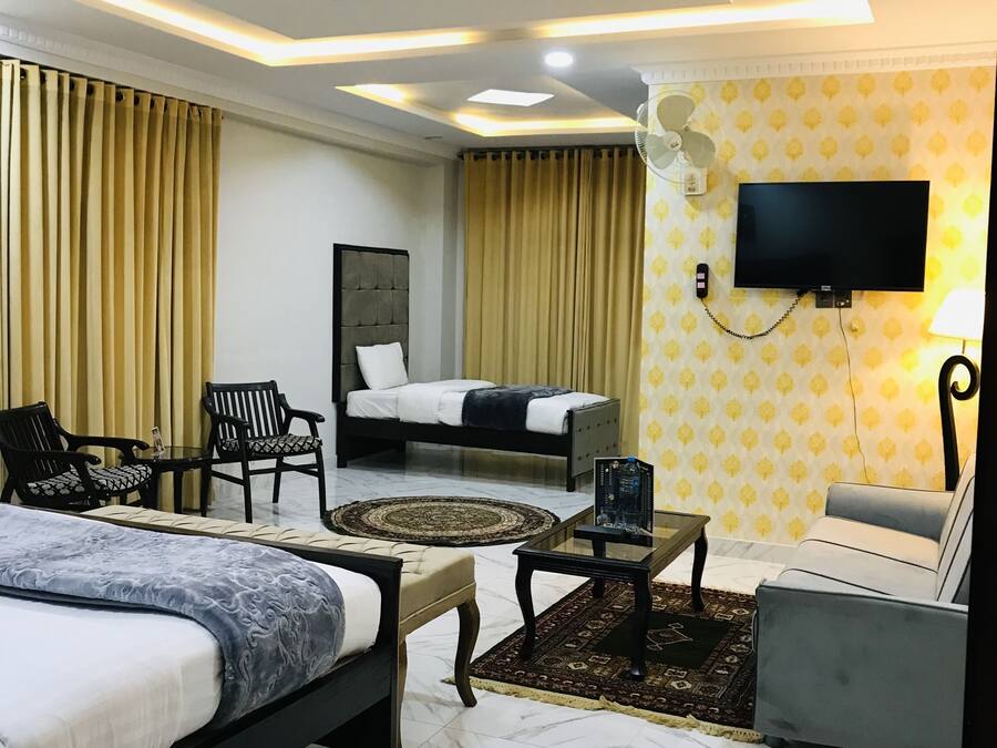 Quarto de hotel com cama, sofá, televisão, escrivaninha e cadeira.