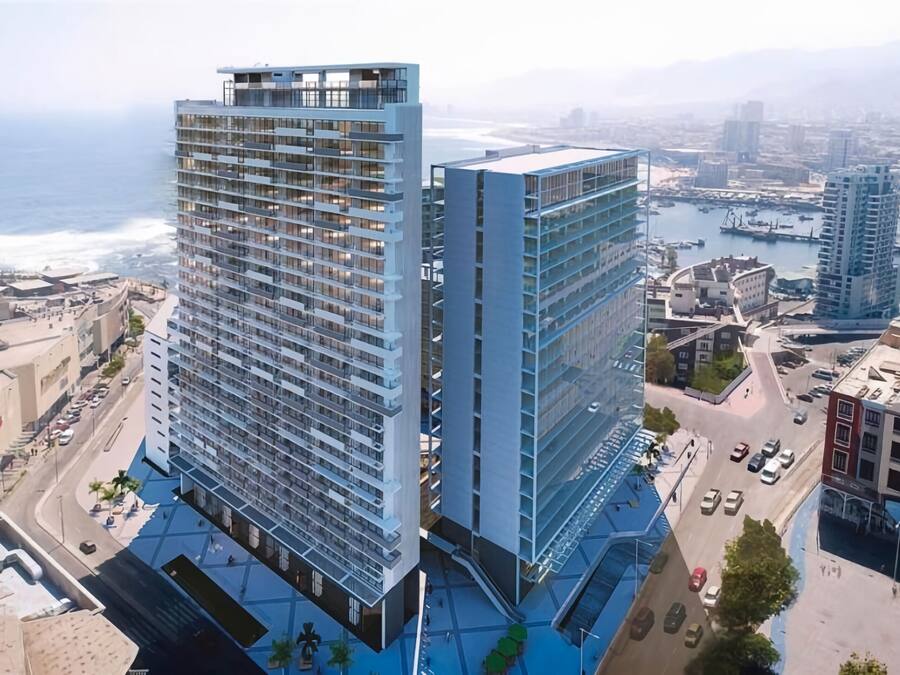 Um edifício alto com vários andares, um terraço no telhado e vista para o oceano.