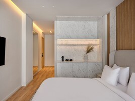 Quarto moderno com cama grande, prateleira embutida com copos e parede de painel de madeira.