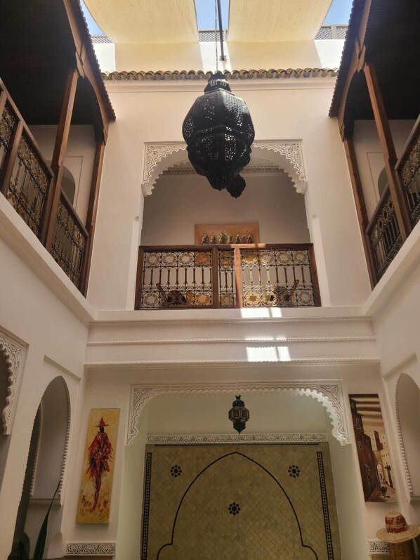 Interior em vários níveis, com grades ornamentadas, um lustre central e um arco decorativo.
