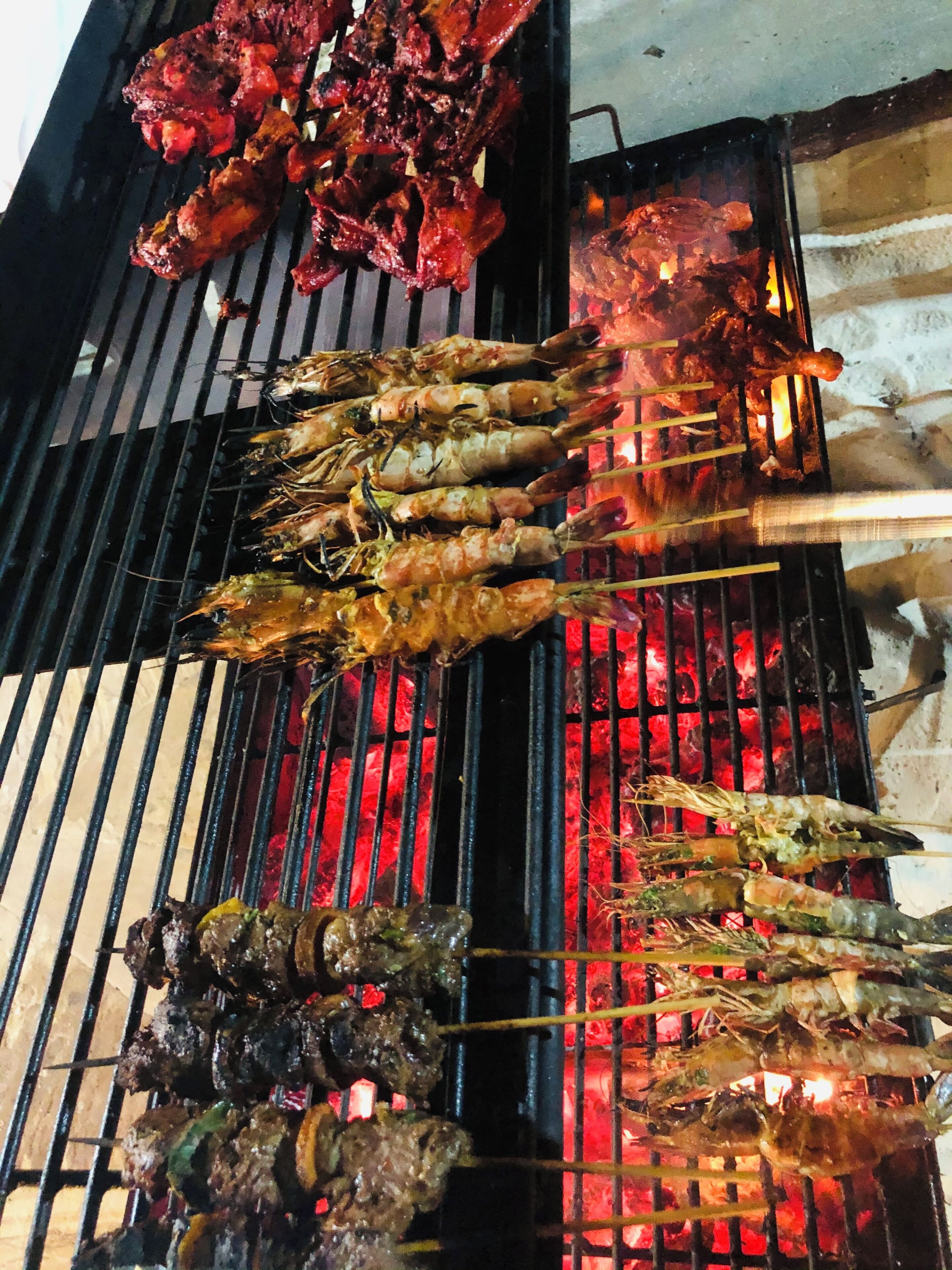 Uma churrasqueira com diversos carnes e frutos do mar sendo preparados.