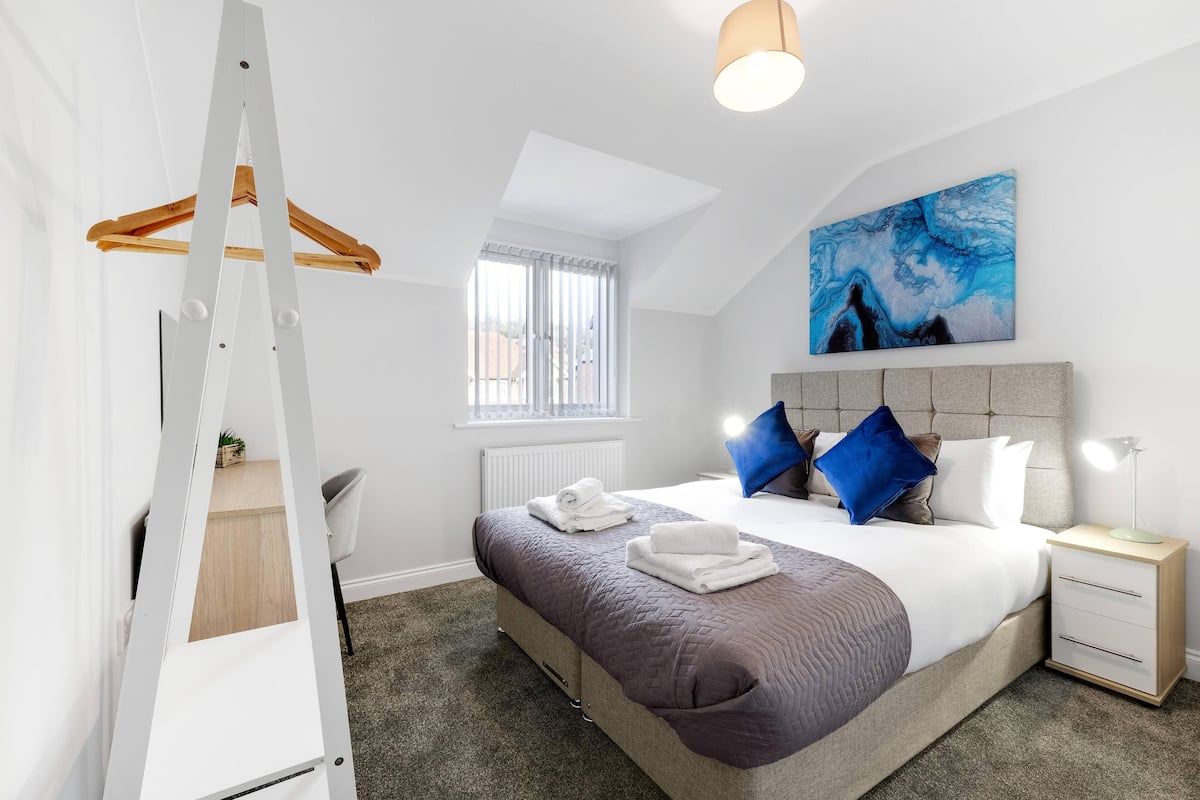 Quarto moderno com cama, mesa de cabeceira e um quadro na parede.