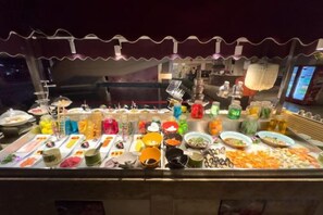 Barraca de comida com diversos pratos e bebidas expostos em um balcão.