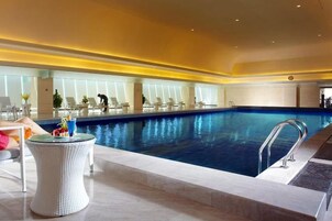 Piscina interna com área de estar, cadeiras e uma mesa com bebidas.