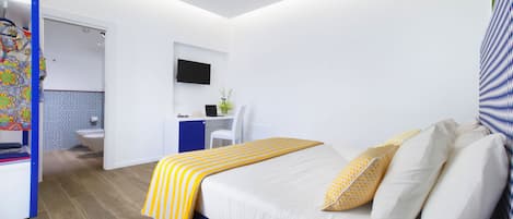 Quarto de hotel moderno com cama, escrivaninha e televisão.