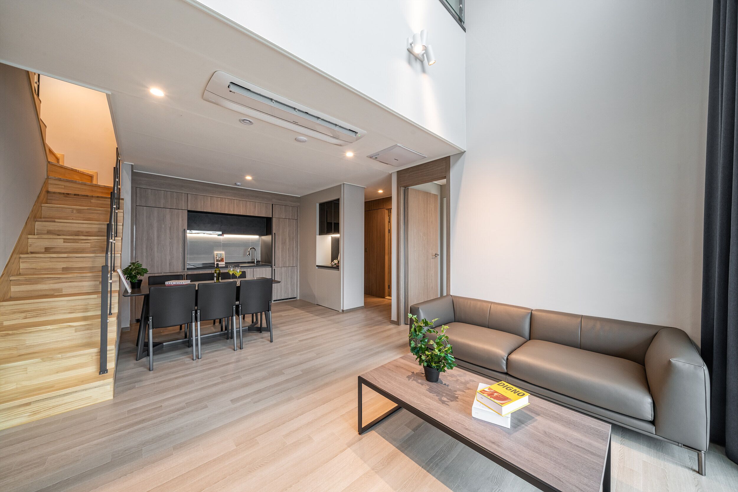 Uma sala de estar moderna com um sofá, uma mesa de centro com uma planta e uma área de jantar com cadeiras e uma mesa.