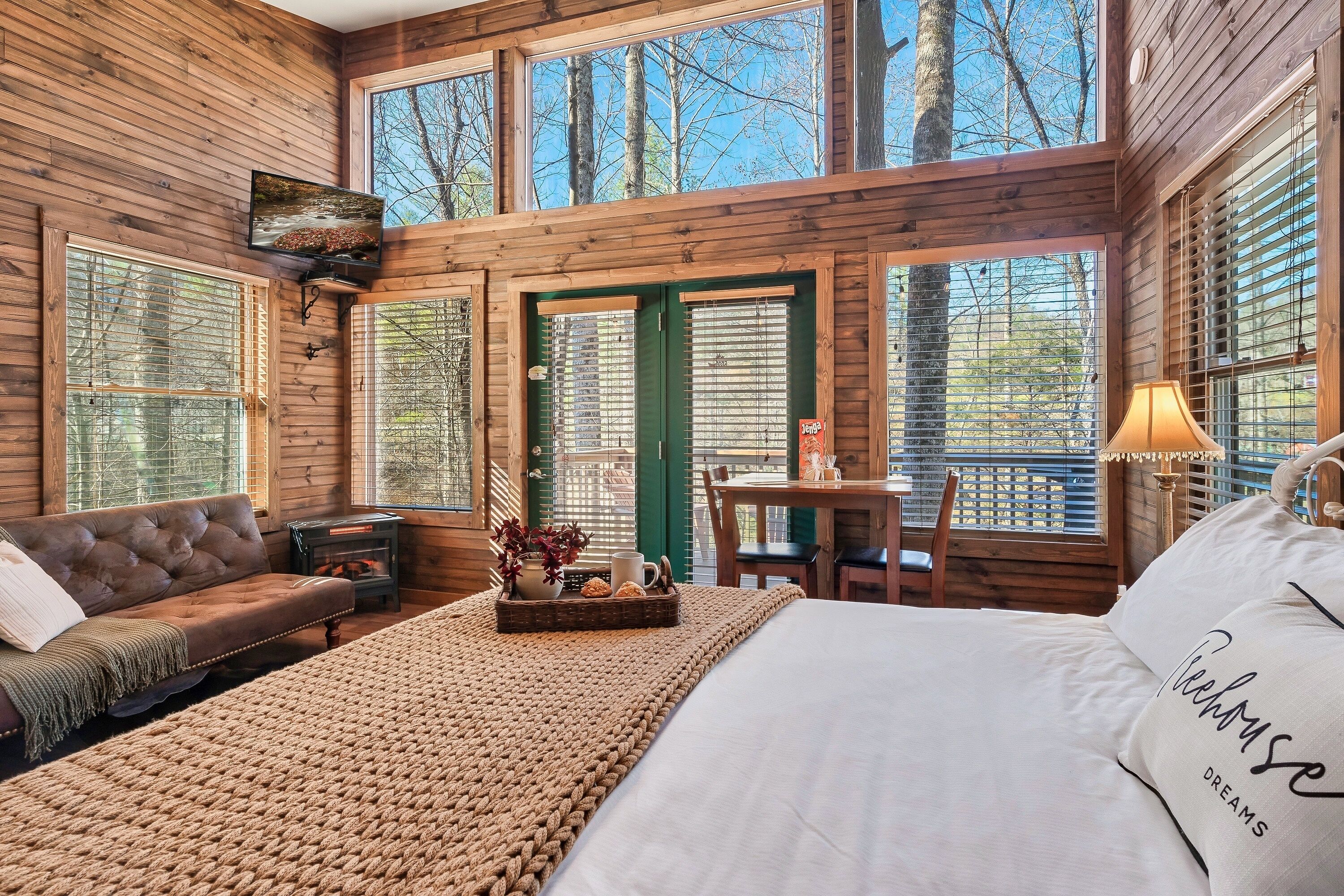 Um quarto de cabana acolhedor, com uma cama, um sofá, uma mesa com cadeiras e uma lareira.