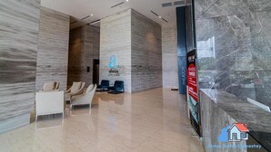 Um lobby moderno de hotel com paredes de mármore, balcão de recepção e área de estar.