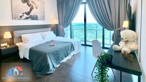 Quarto de hotel moderno com cama, abajures, escrivaninha com um ursinho de pelúcia, planta em vaso e uma grande janela com cortinas.