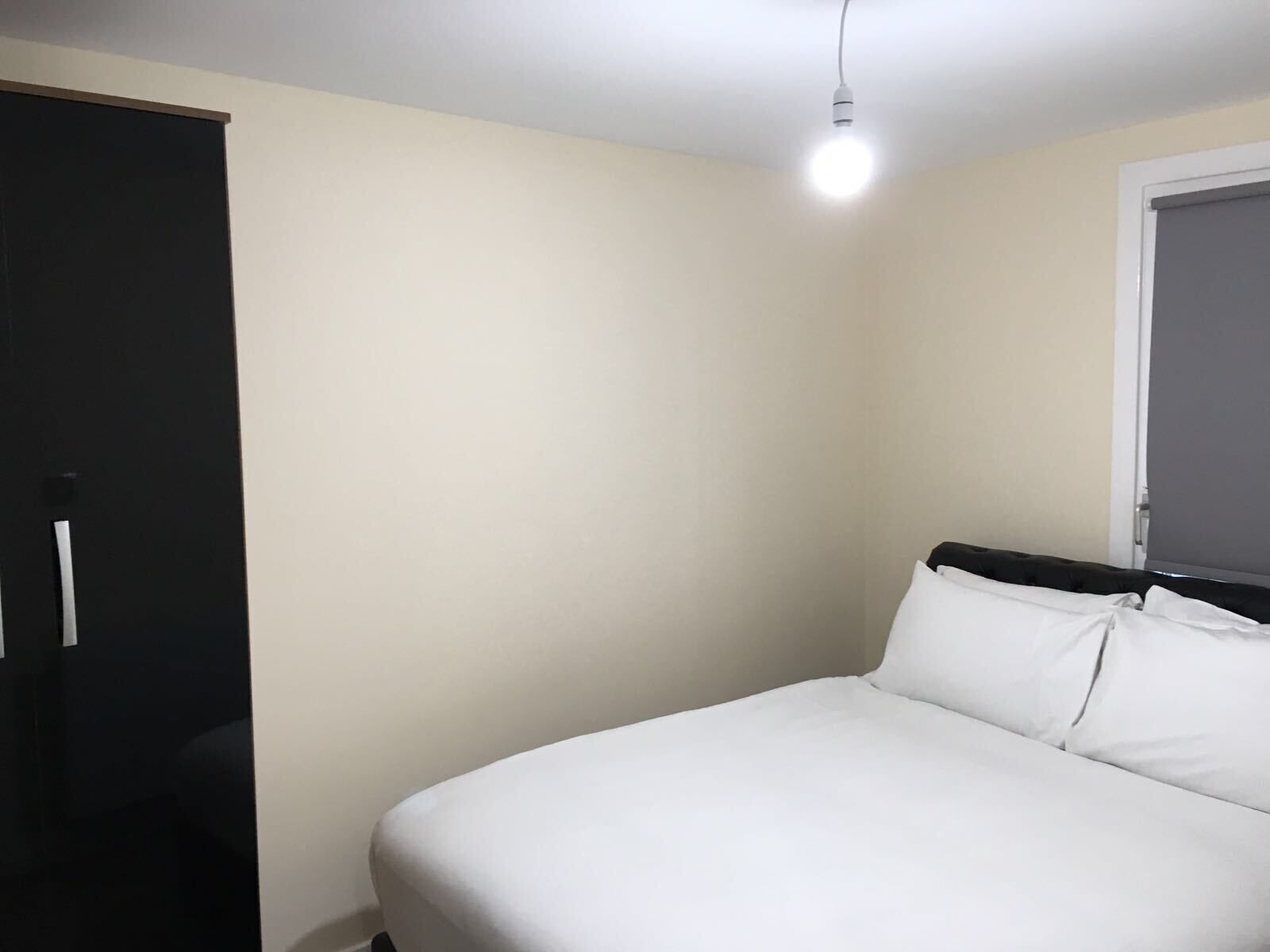 Quarto com cama, porta e luminária.