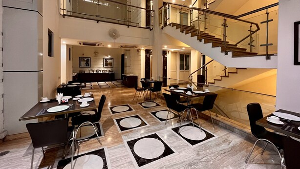 Um amplo espaço de refeições de hotel, com várias mesas, cadeiras e um bar central.