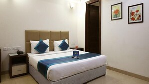Quarto de hotel com cama, mesas de cabeceira, ar condicionado e duas imagens emolduradas na parede.
