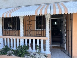 Um edifício com varanda coberta, colunas e portão.