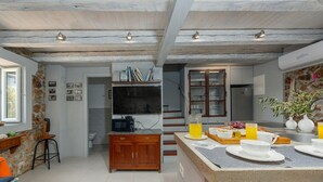 Uma cozinha com ilha de madeira, parede de pedra e área de refeições com mesa de café da manhã.