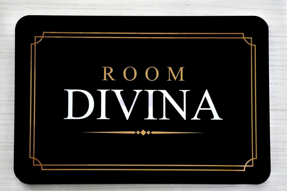 Um tapete preto com as palavras "ROOM DIVINA" em texto dourado e branco, emoldurado por uma borda dourada.