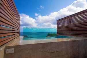 Uma área de piscina moderna com vista desobstruída para o oceano e céu nublado.