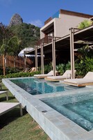 Piscina com espreguiçadeiras e vista para uma montanha.