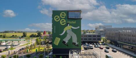 Um hotel com um grande outdoor anunciando uma pessoa caminhando com mala.