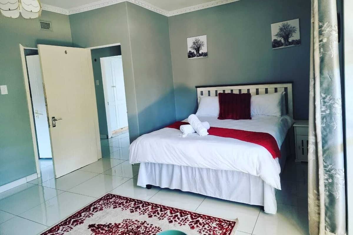 Quarto com cama, porta branca e tapete vermelho e branco.
