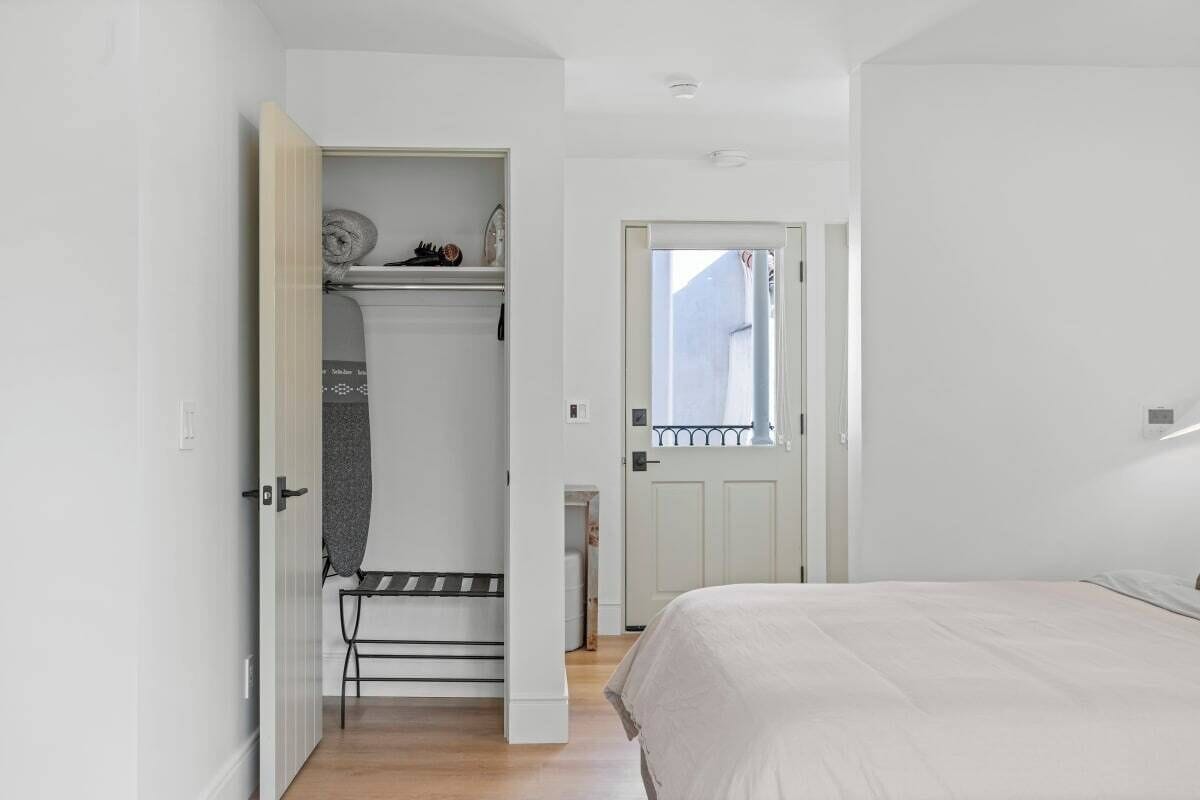 Quarto com uma cama, porta, janela e uma pequena mesa.