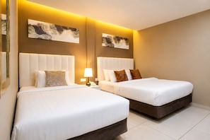 Quarto de hotel com duas camas, uma mesa de cabeceira com abajur e obras de arte nas paredes.