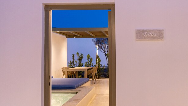 Uma área de estar moderna ao ar livre com piscina, mesa e cadeiras.