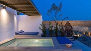 Área moderna para banheira de hidromassagem ao ar livre, com pérgola de madeira, espaço de estar com almofadas e uma cadeira suspensa.