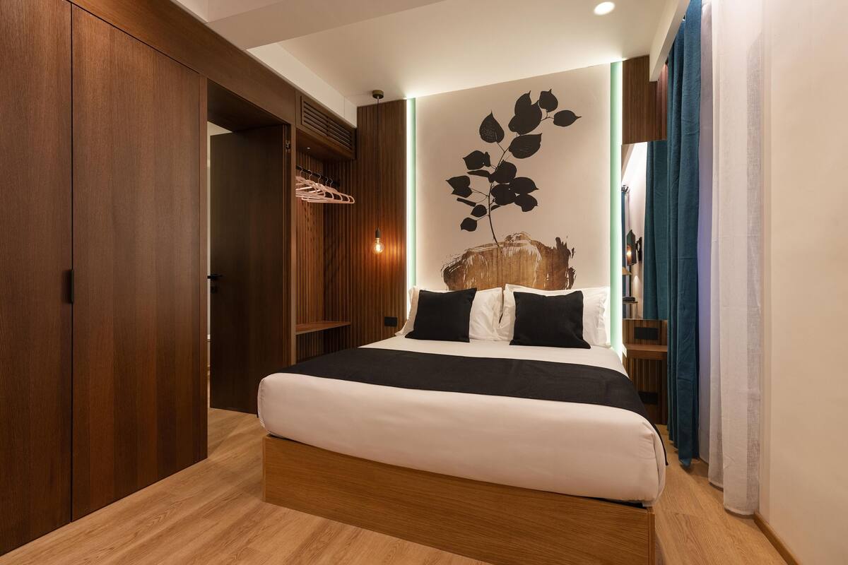Quarto moderno com cama de madeira, guarda-roupa e planta suspensa na parede.